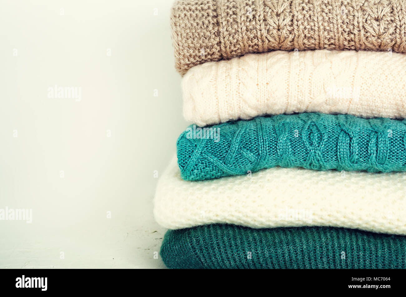 Pile of knitted wool sweaters on white background with copy space ...