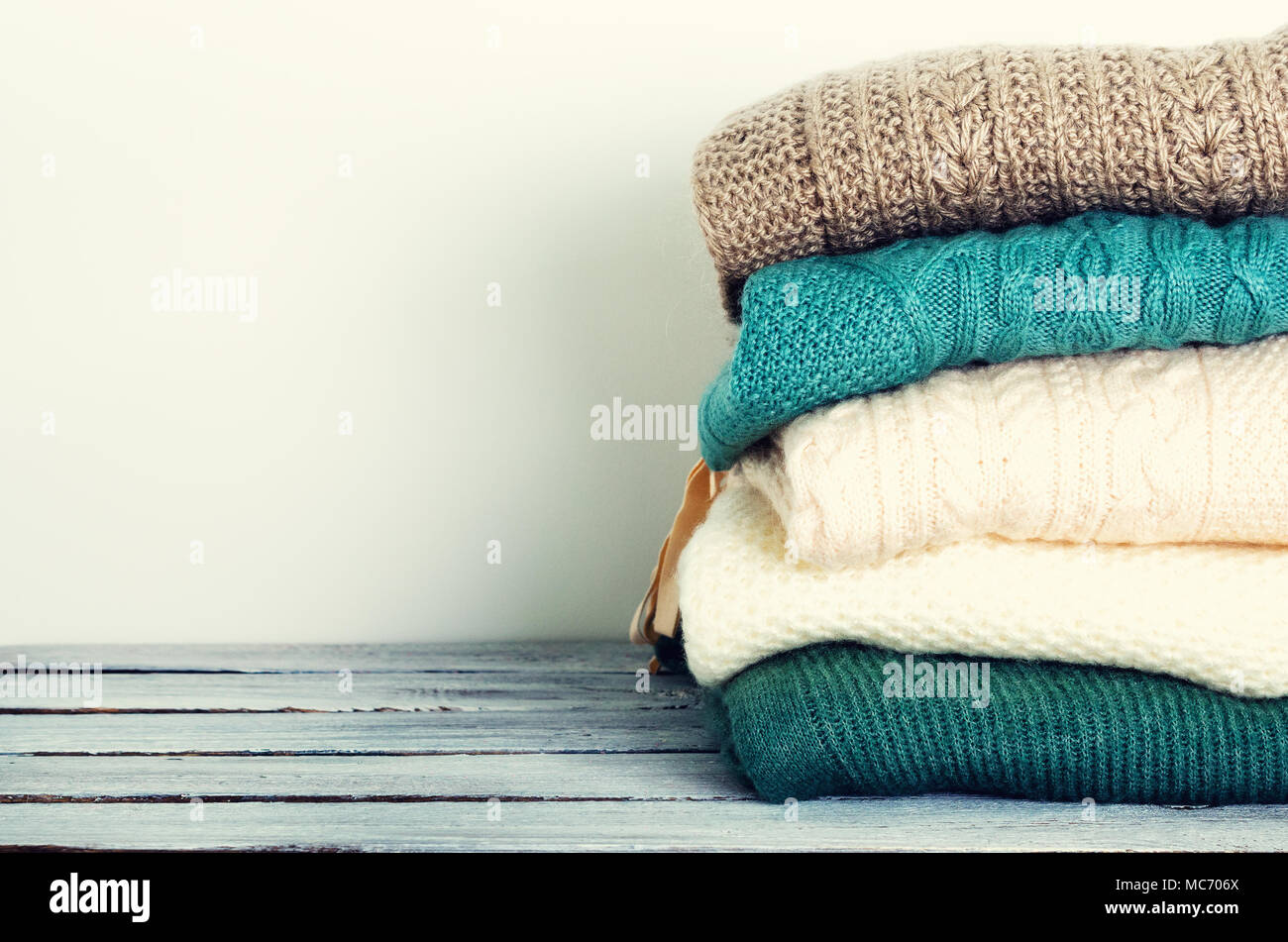 Pile of knitted wool sweaters on white background with copy space ...