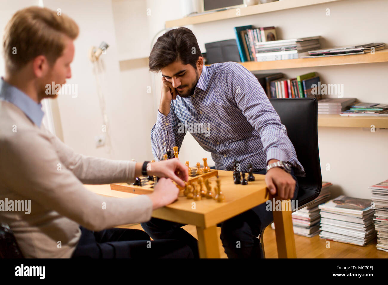 Two young men playing chess in room Stock Photo - Alamy