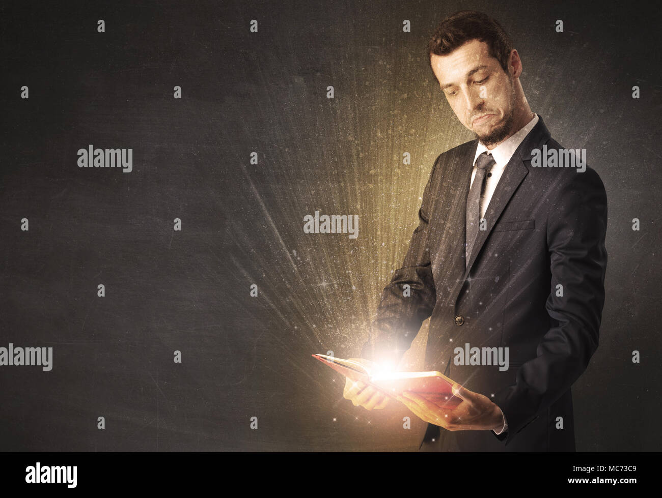 Man holding and reading a shiny book Stock Photo - Alamy