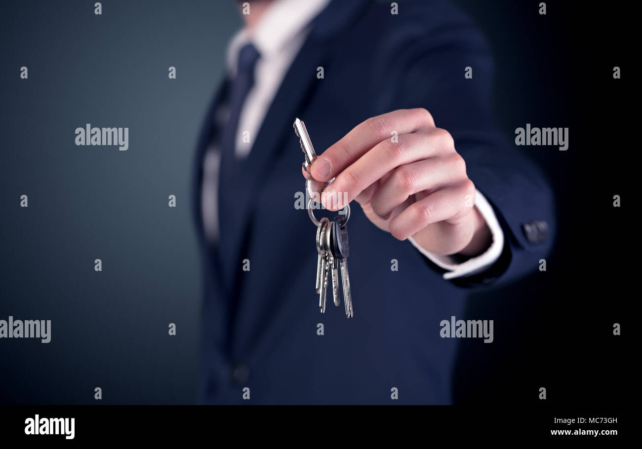 Young businessman hand over keys with empty dark background Stock Photo ...