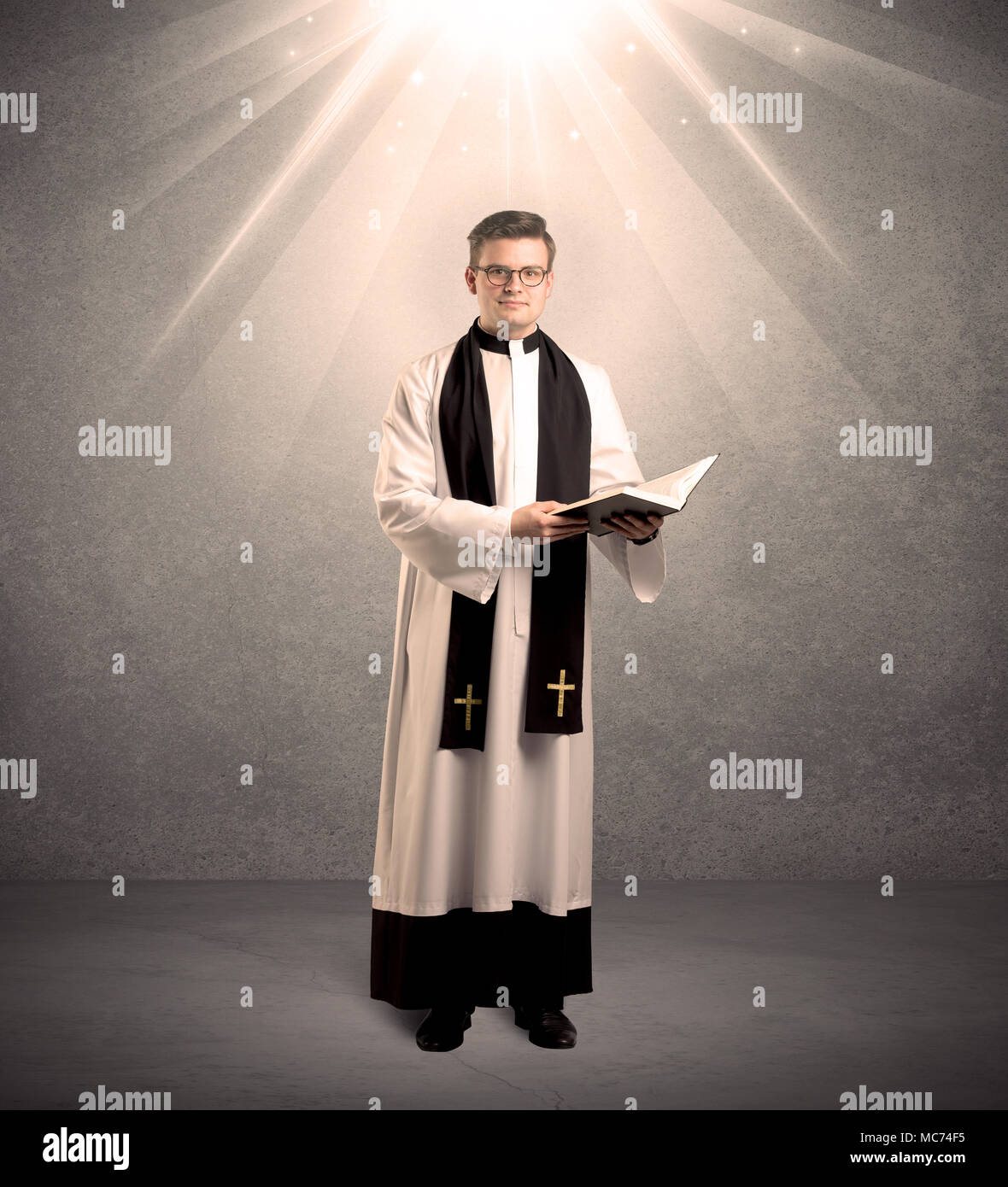 A male religious young priest in black and white dress giving his ...
