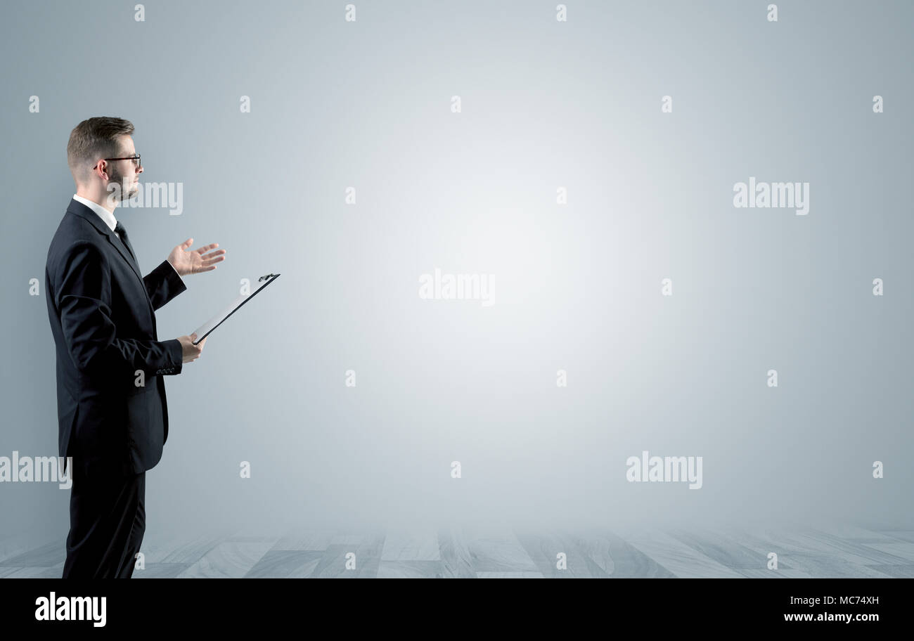 Elegant businessman standing and presenting something in an empty space ...