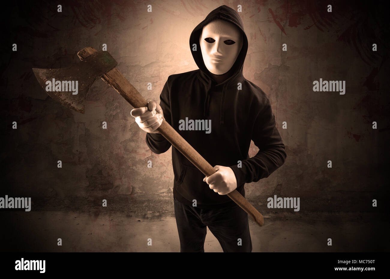 Armed rude assassin in an empty bloody room concept with gun ax ...