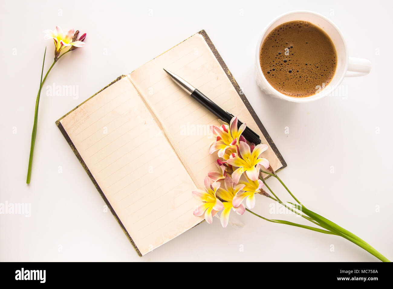 Colorful spring flowers, with blank open diary for text and cup of ...