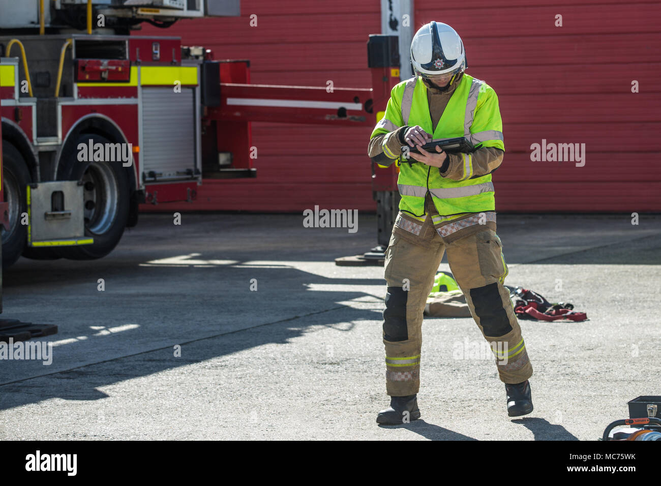 Single fireman using computer tablet at work outside next to fire ...