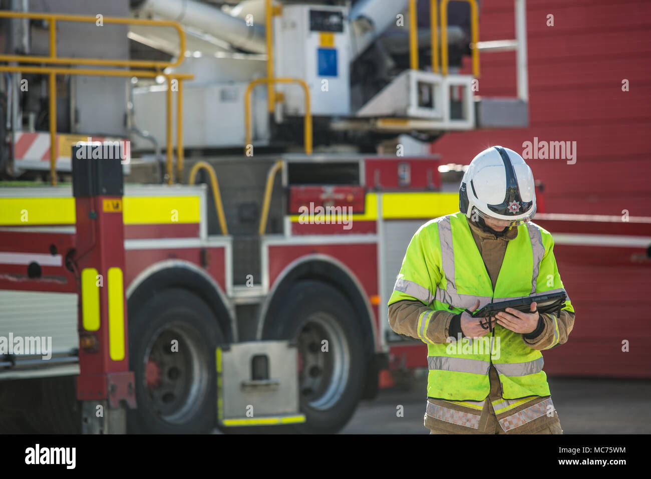 Single fireman using computer tablet at work outside next to fire ...