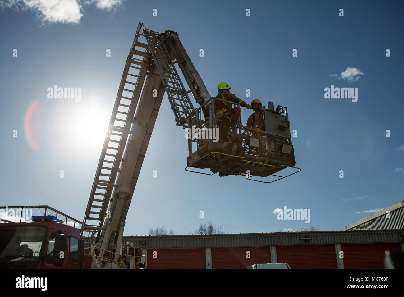 silhouette of Firefighters being elevated on fire engine turntable ...