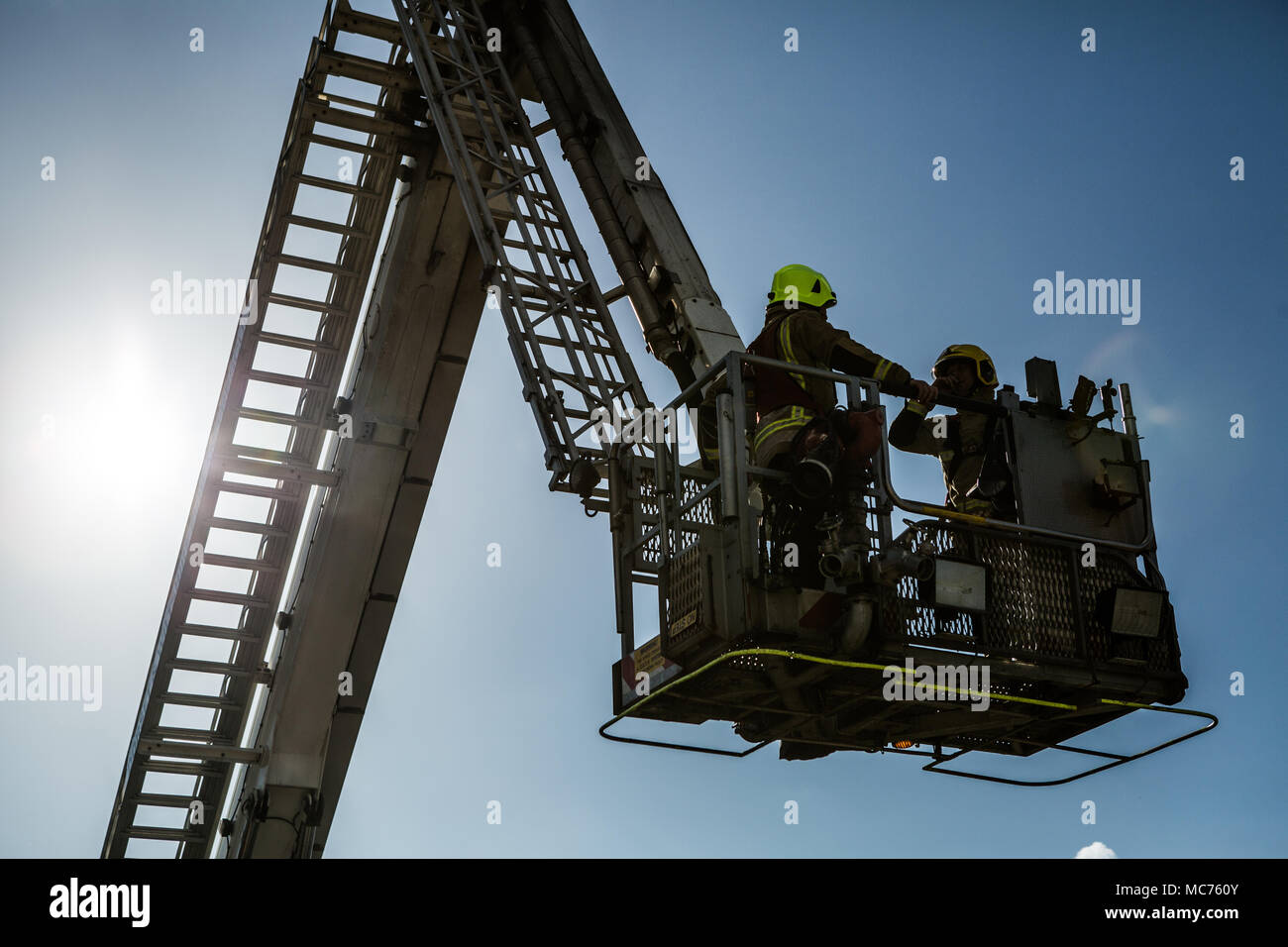 silhouette of Firefighters being elevated on fire engine turntable ...