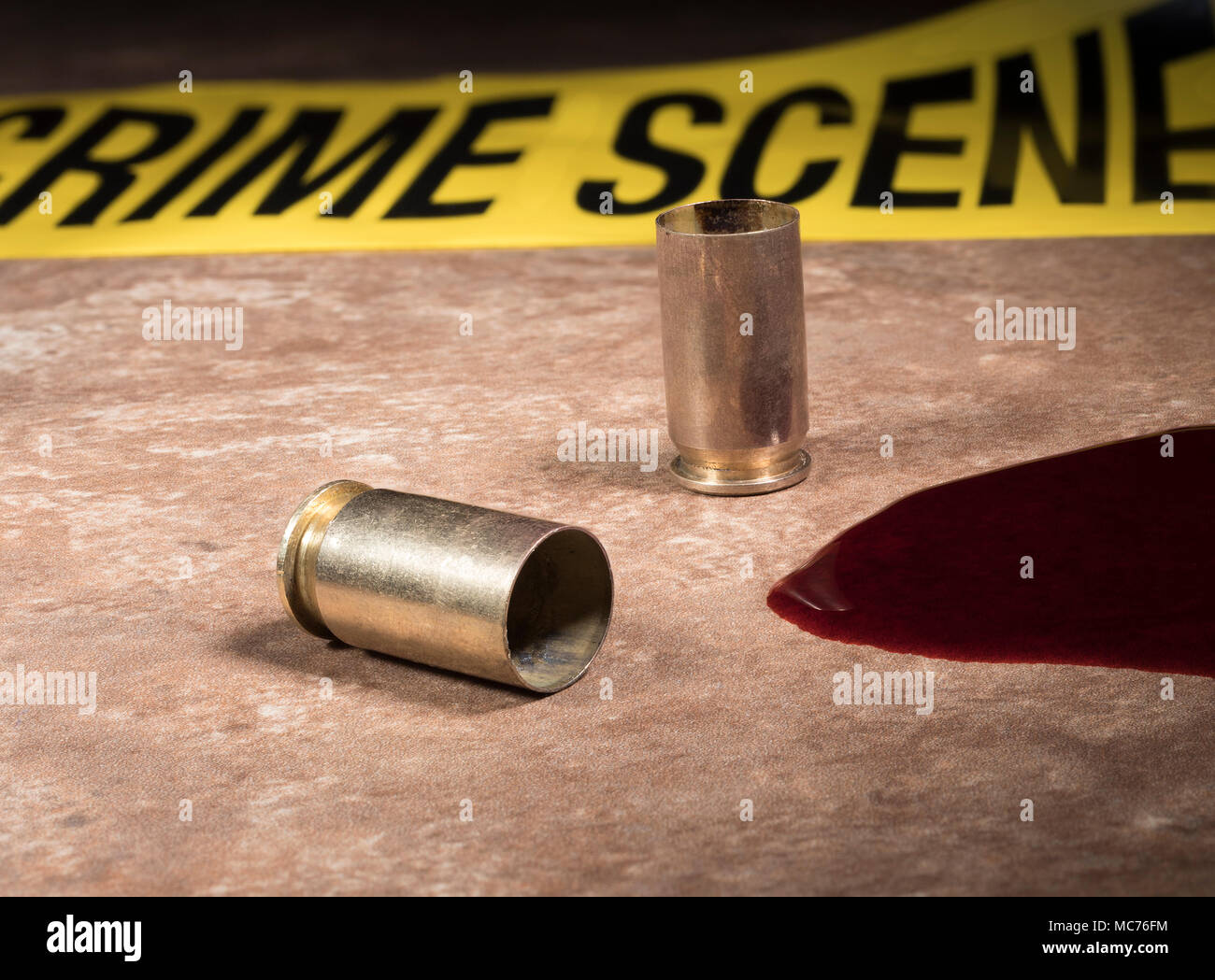 Pistol brass and blood on a tan tile with police tape behind Stock ...