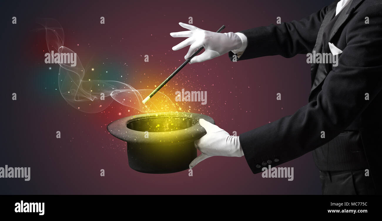 Illusionist hand starts to conjure with white glove and magic wand ...
