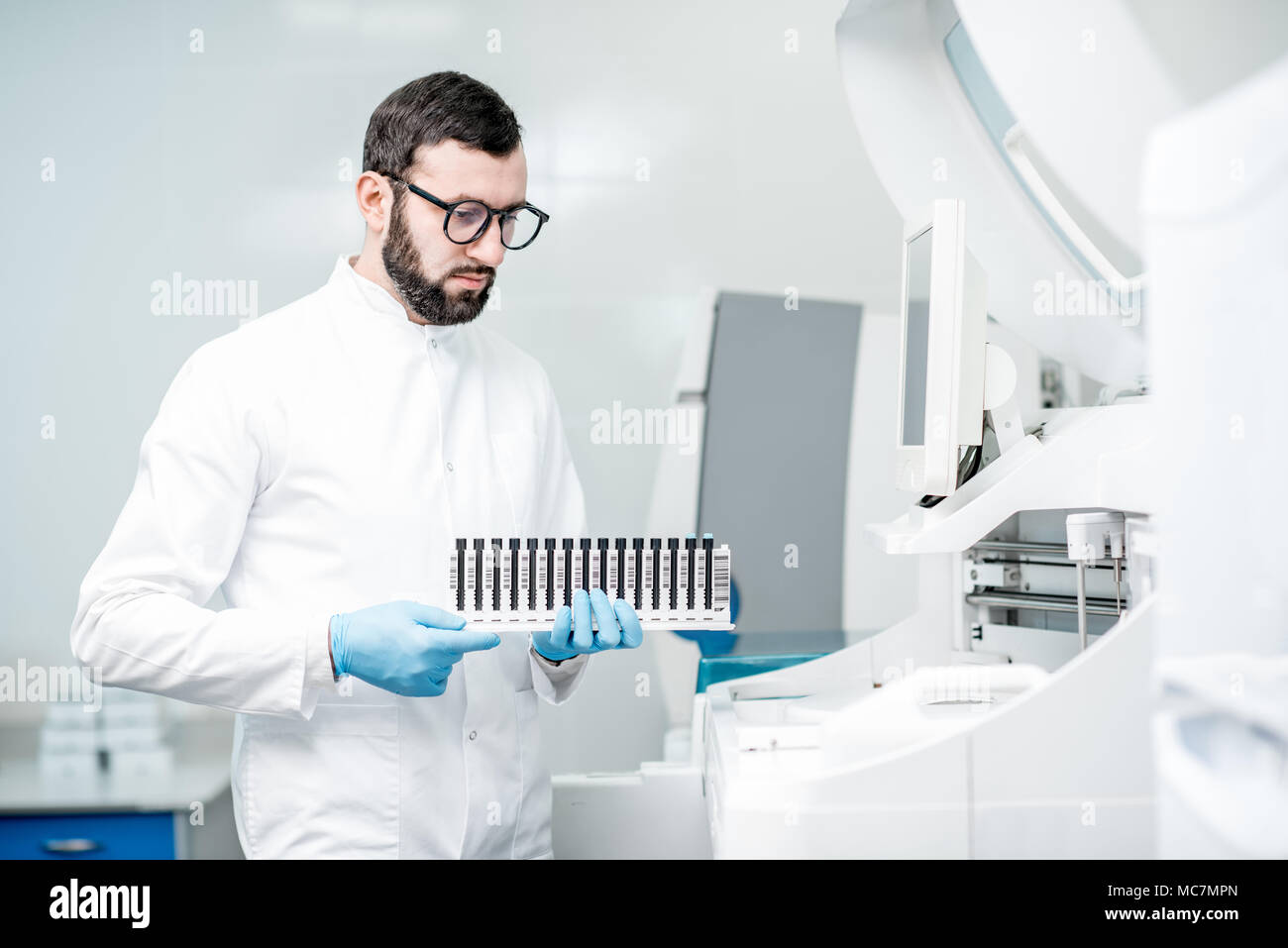 Male laboratory assistant in uniform holding test tubes near the ...