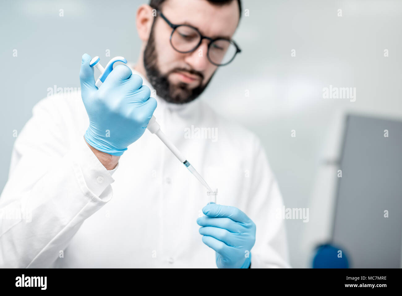 Man putting sample into the test tube at the laboratory, close-up view ...
