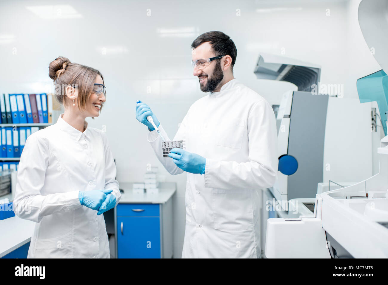 Couple of laboratory assistants in uniform working with test tubes ...