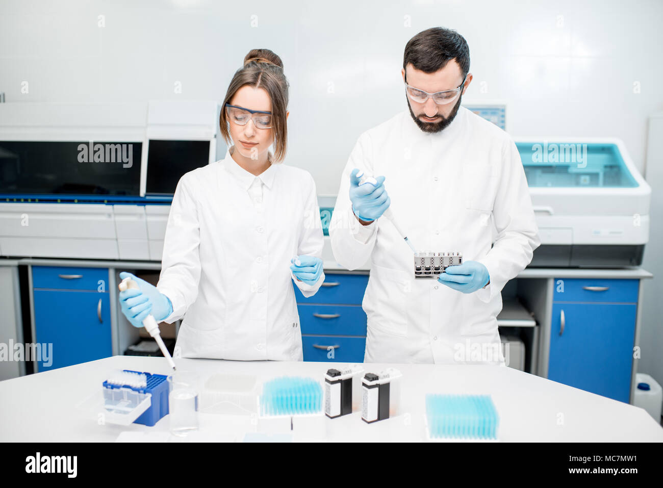 Couple of laboratory assistants in uniform working with analysis in ...