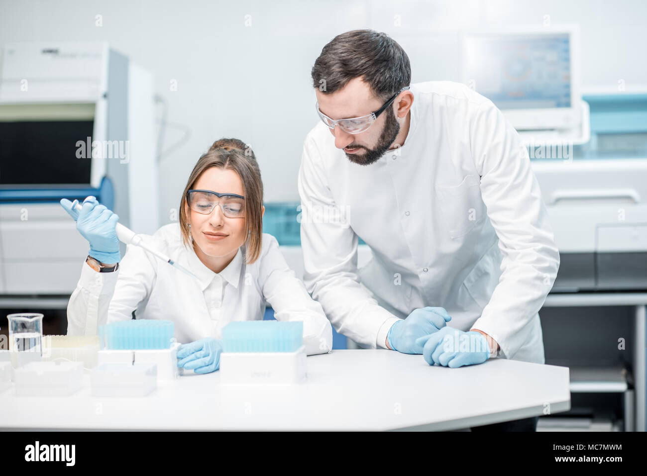 Laboratory assistants in uniform and protective glasses working with ...