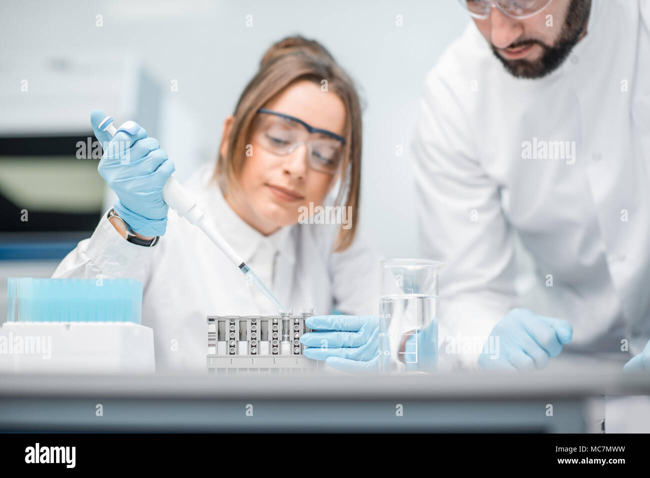 Laboratory assistants in uniform and protective glasses working with ...