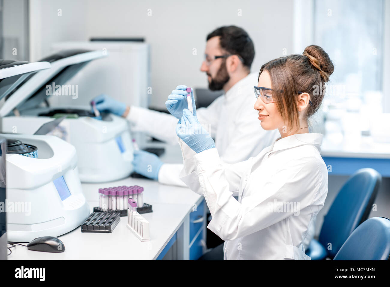 Laboratory assistants making analysis with test tubes and analyzer ...