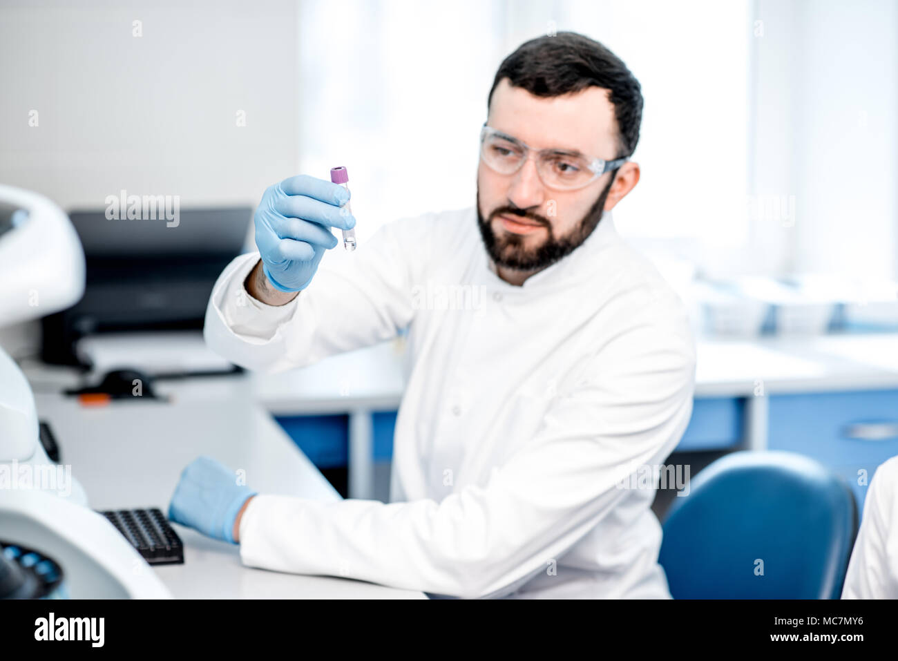 Male laboratory assistant checking test tube sitting at the modern ...
