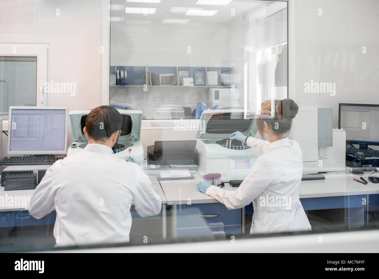 View through the glass on the laboratory with medic doing analysis ...