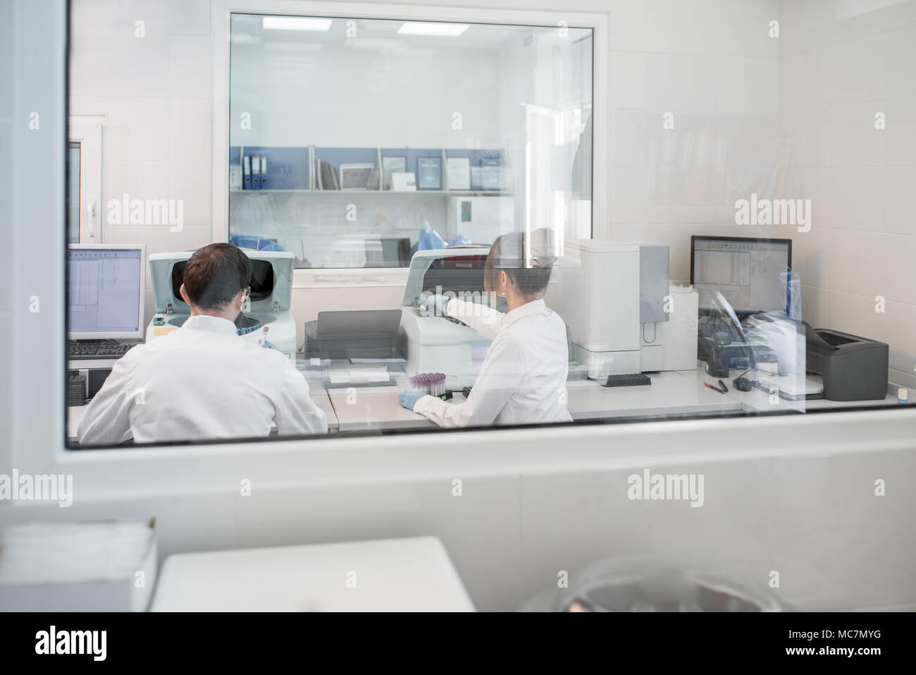 View through the glass on the laboratory with medic doing analysis ...