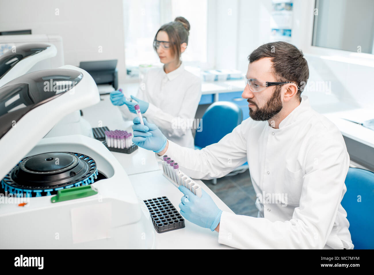 Laboratory assistants making analysis with test tubes and analyzer ...