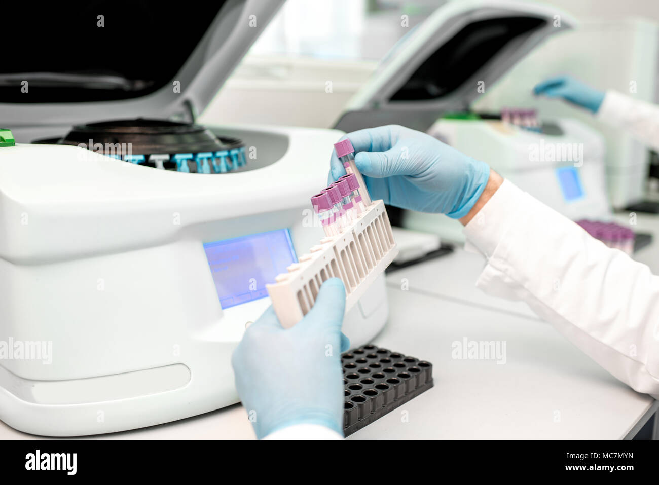 Laboratory assistant putting test tubes into the holder of analyzer ...