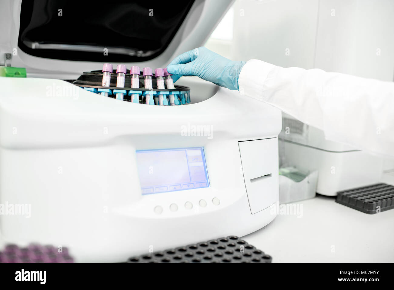 Laboratory assistant putting test tubes into the holder of analyzer ...