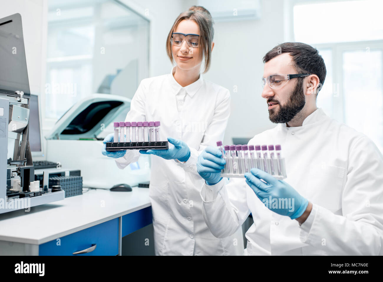 Portrait of a male laboratory assistant making analysis with test tubes ...
