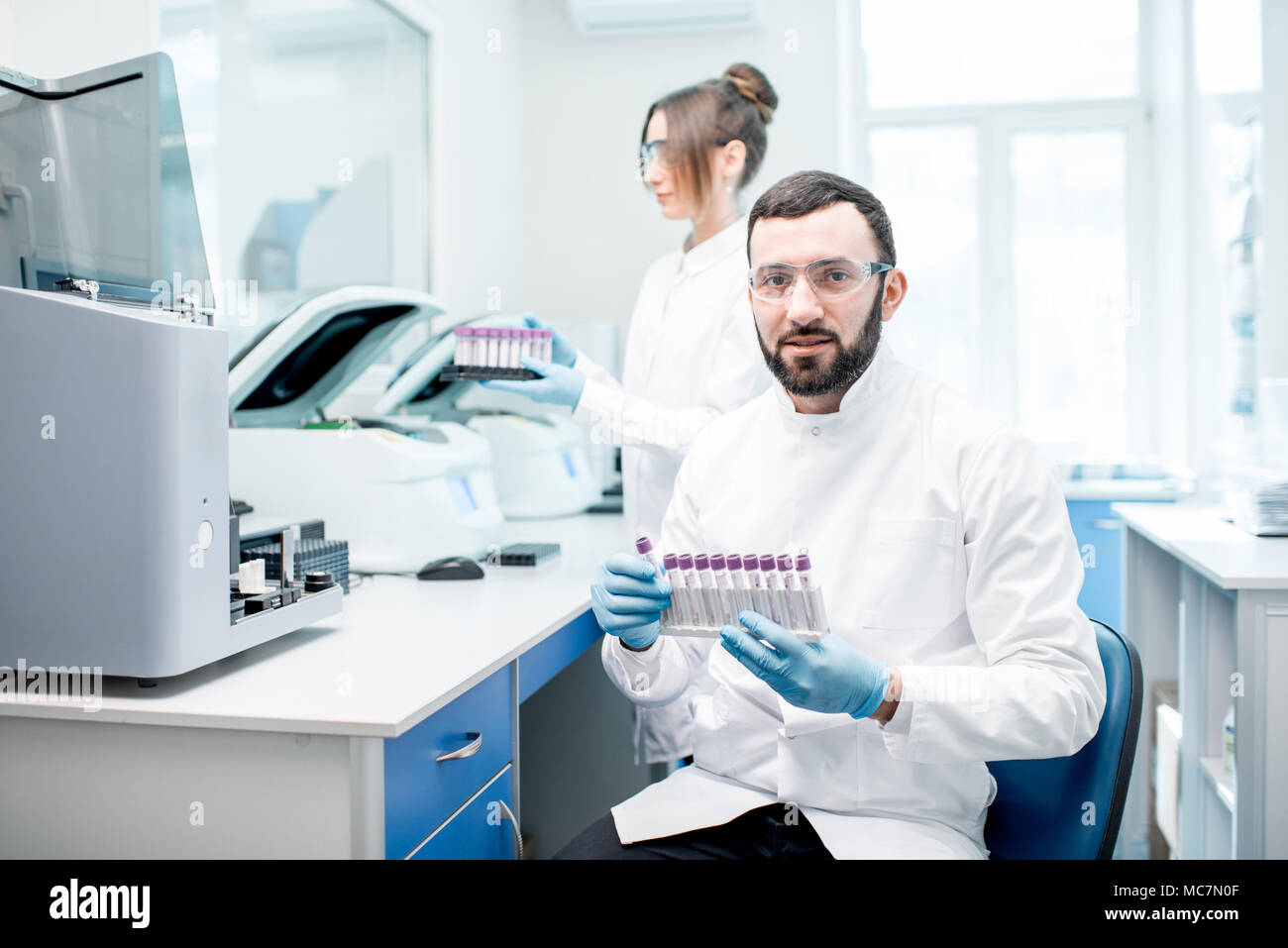 Portrait of a male laboratory assistant making analysis with test tubes ...