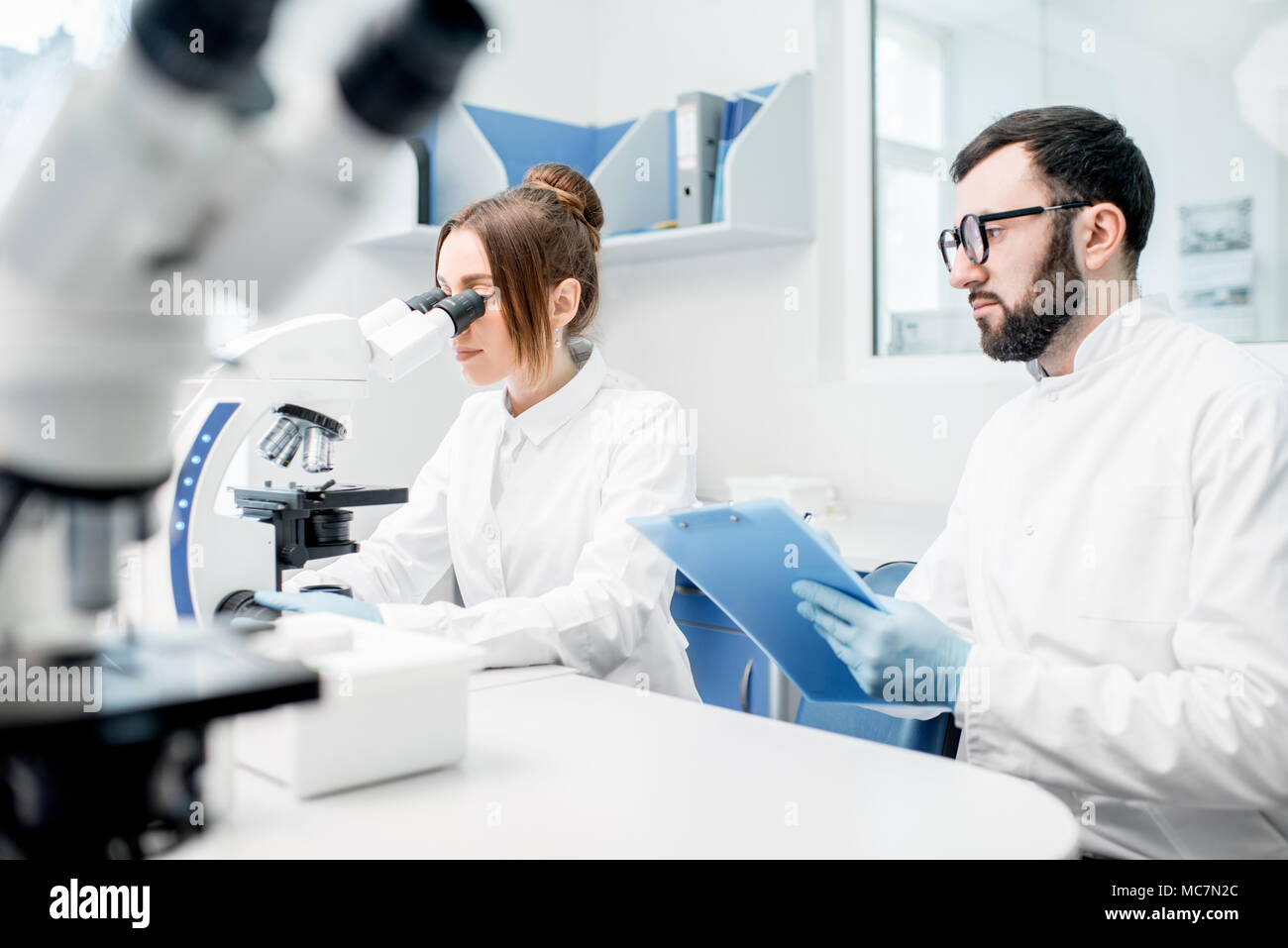 Medics in uniform working with microscope making analysis at the ...