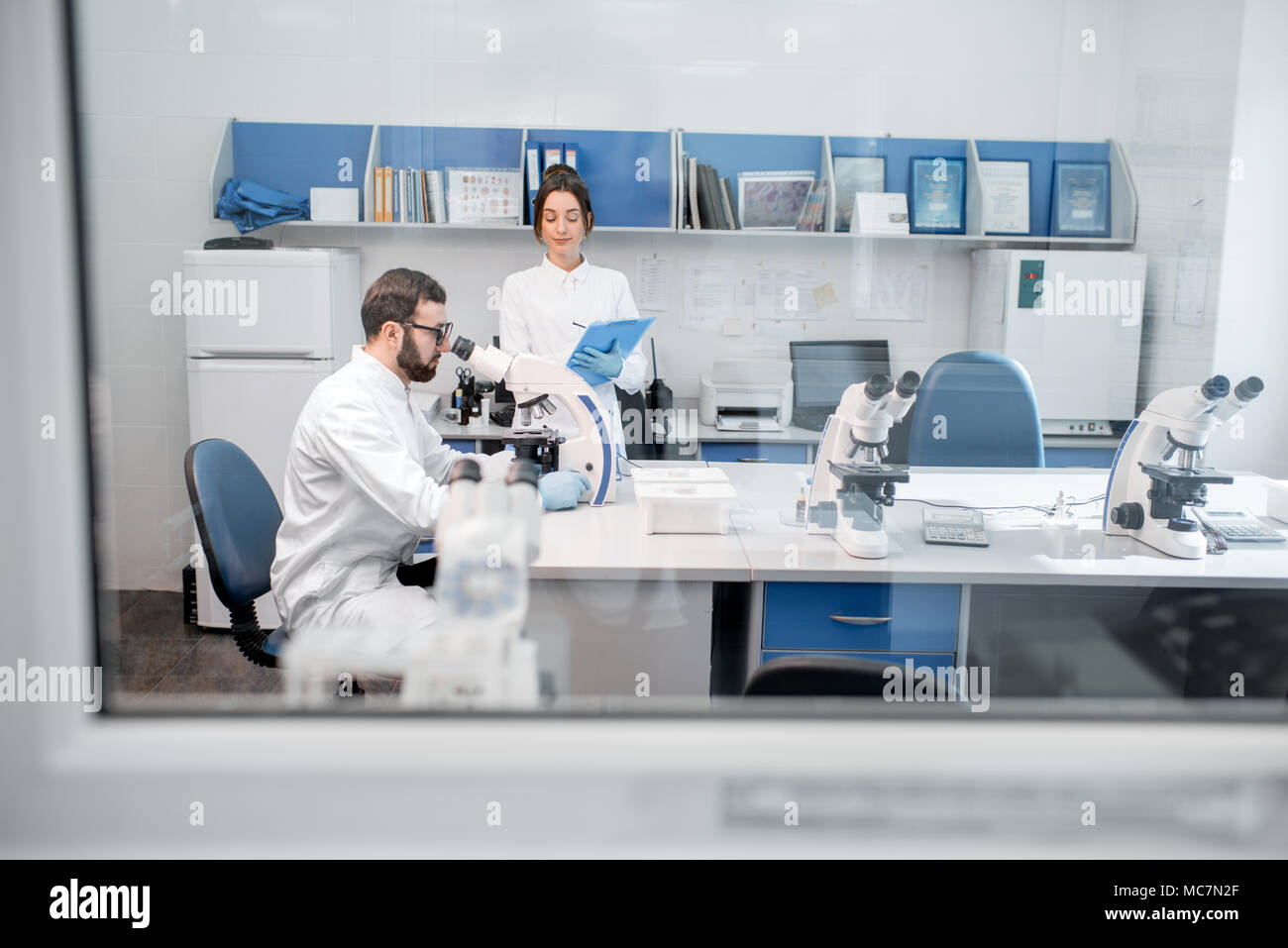 View through the window on the laboratory office with medics working ...