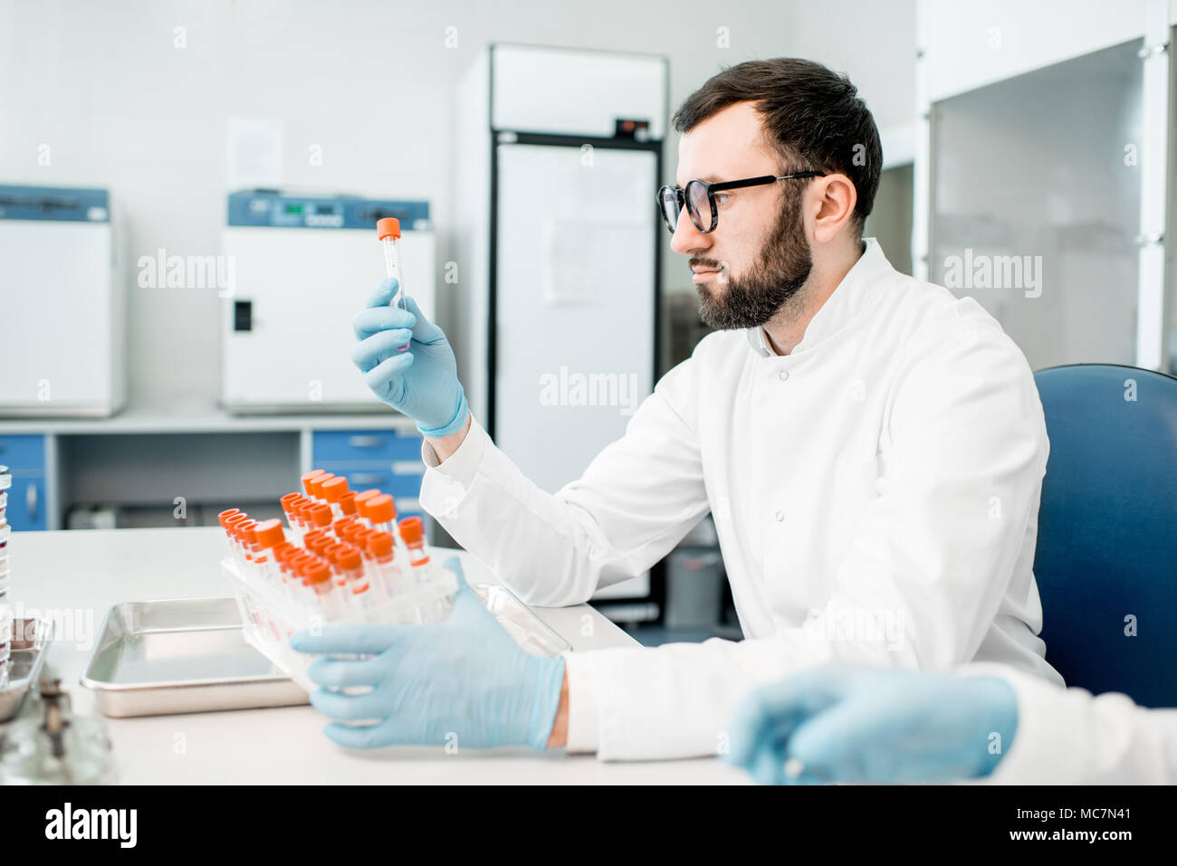 Male laboratory assistant examining test tube in the bacteriological ...