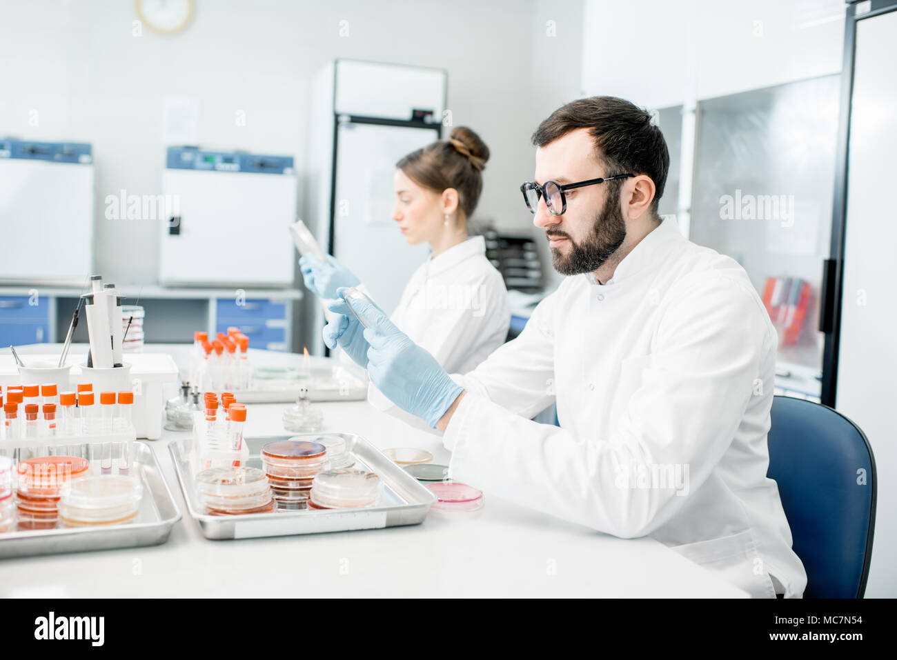 Couple of medics in uniform making bacteriological tests sitting in the ...