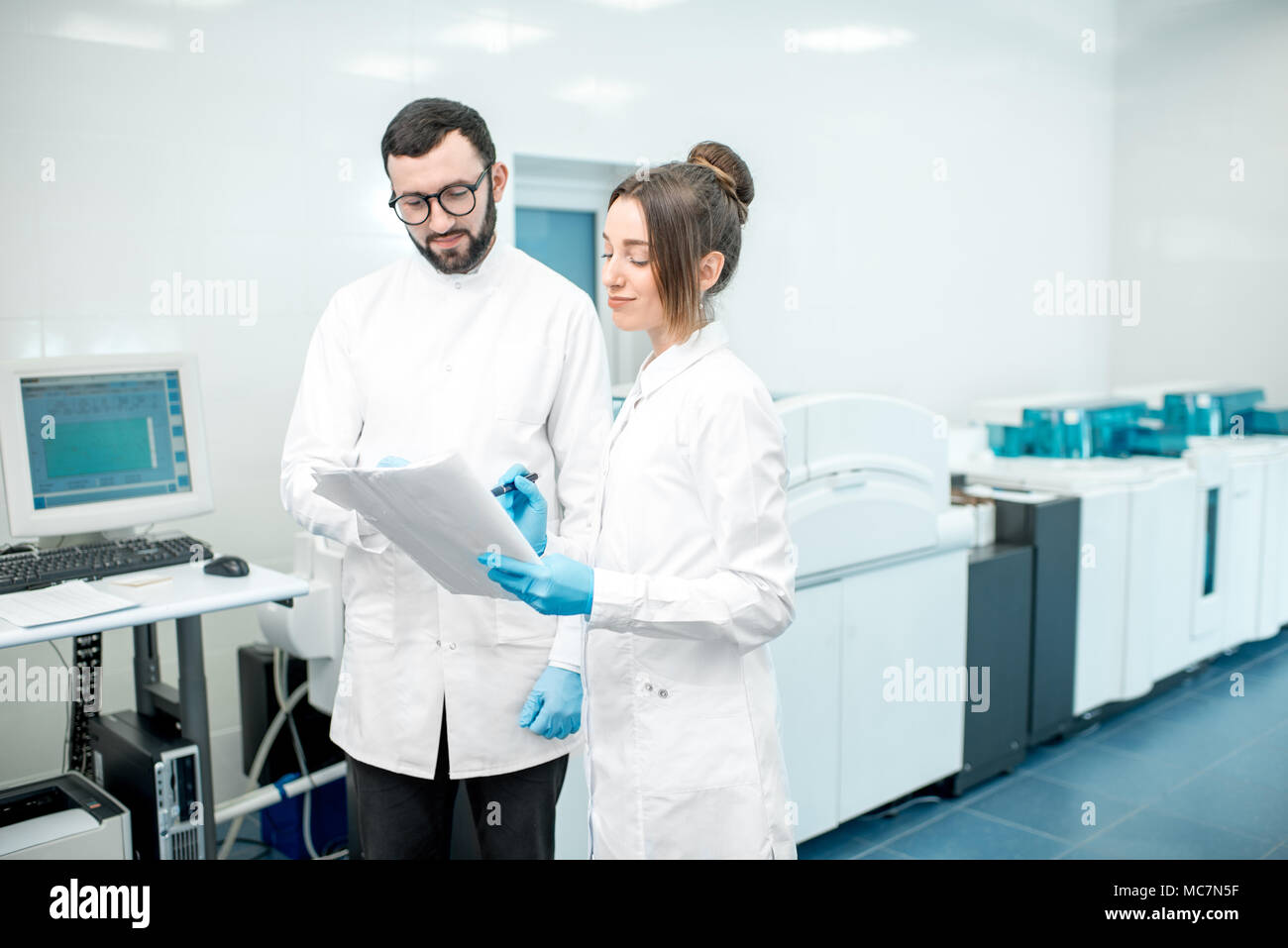 Couple of medics working with paper documets standing in the laboratory ...