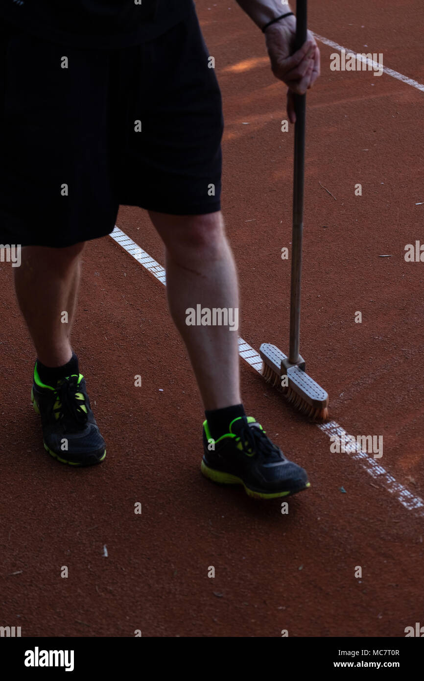 Man in shorts cleaning tennis court lines with a broom Stock Photo - Alamy