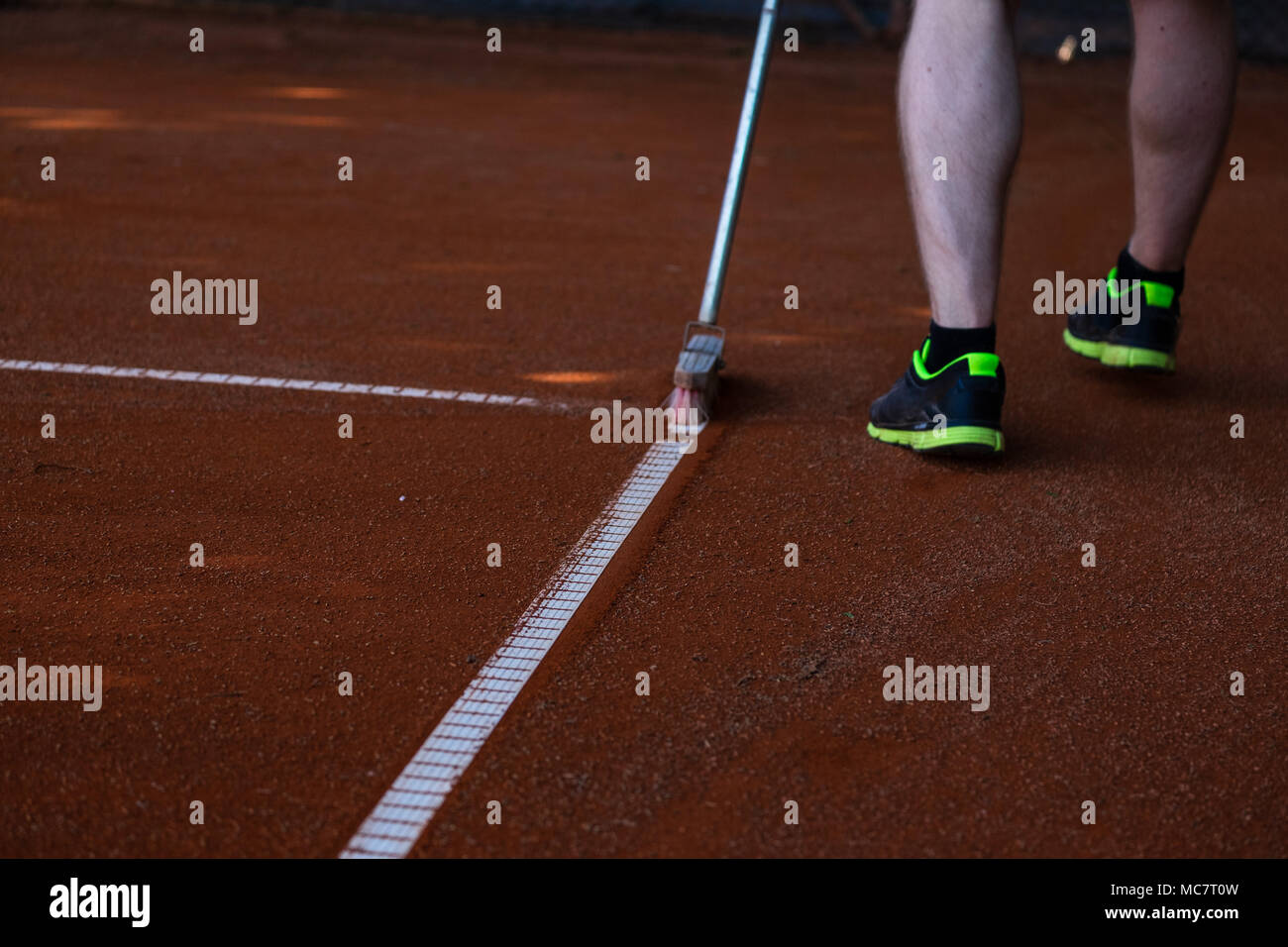 Man in shorts cleaning tennis court corner lines with a broom Stock ...