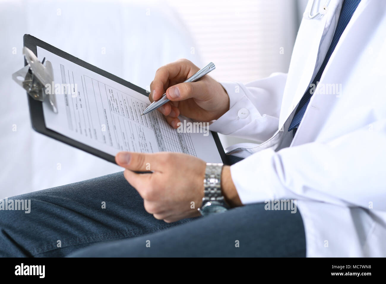 Doctor man filling up medical form on clipboard closeup. Healthcare ...