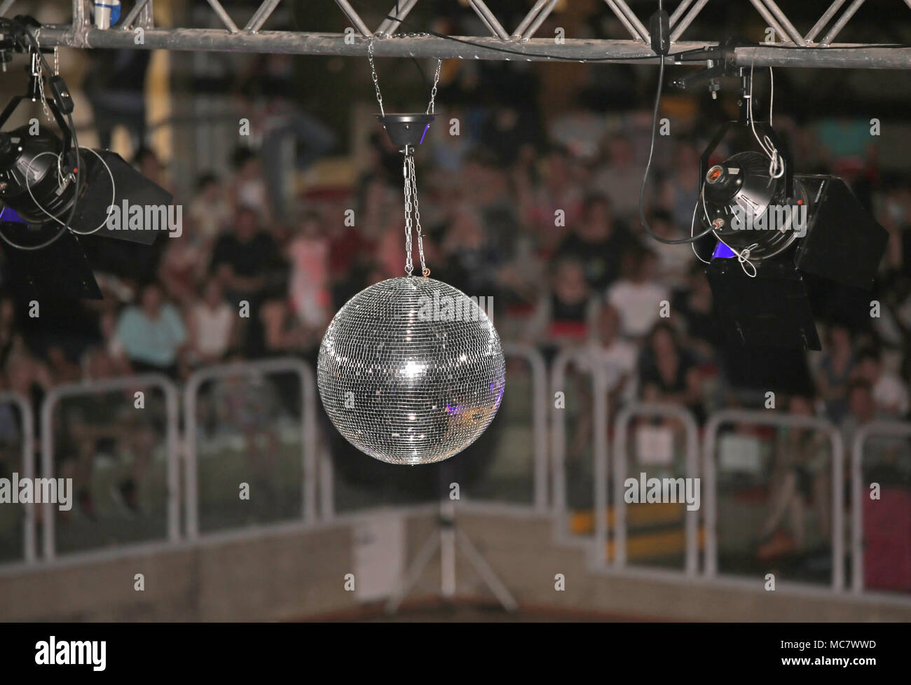 Big disco ball at the concert that reflects light directed at it in ...