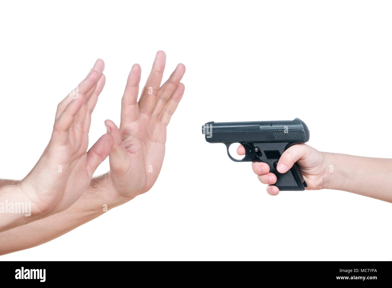 Child hand with a gun aiming at the male hands showing a stop isolated ...