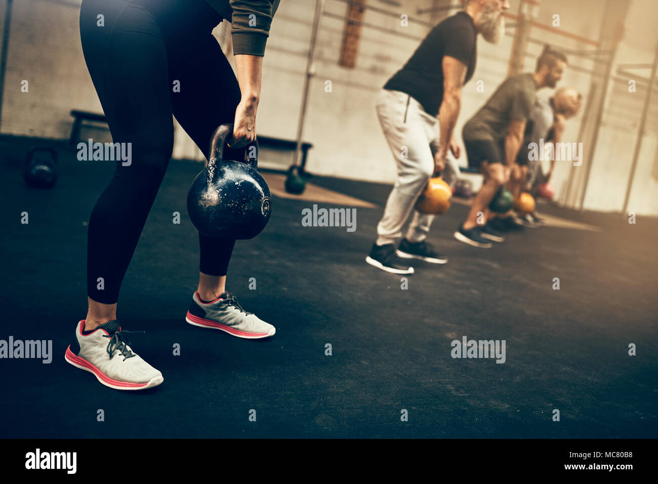 Fit group of people in workout gear lifting dumbbells during an ...