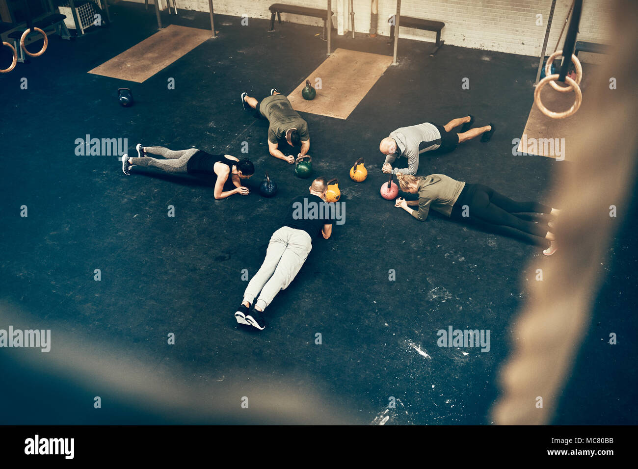 High angle of a group of fit people planking together on the floor of a ...