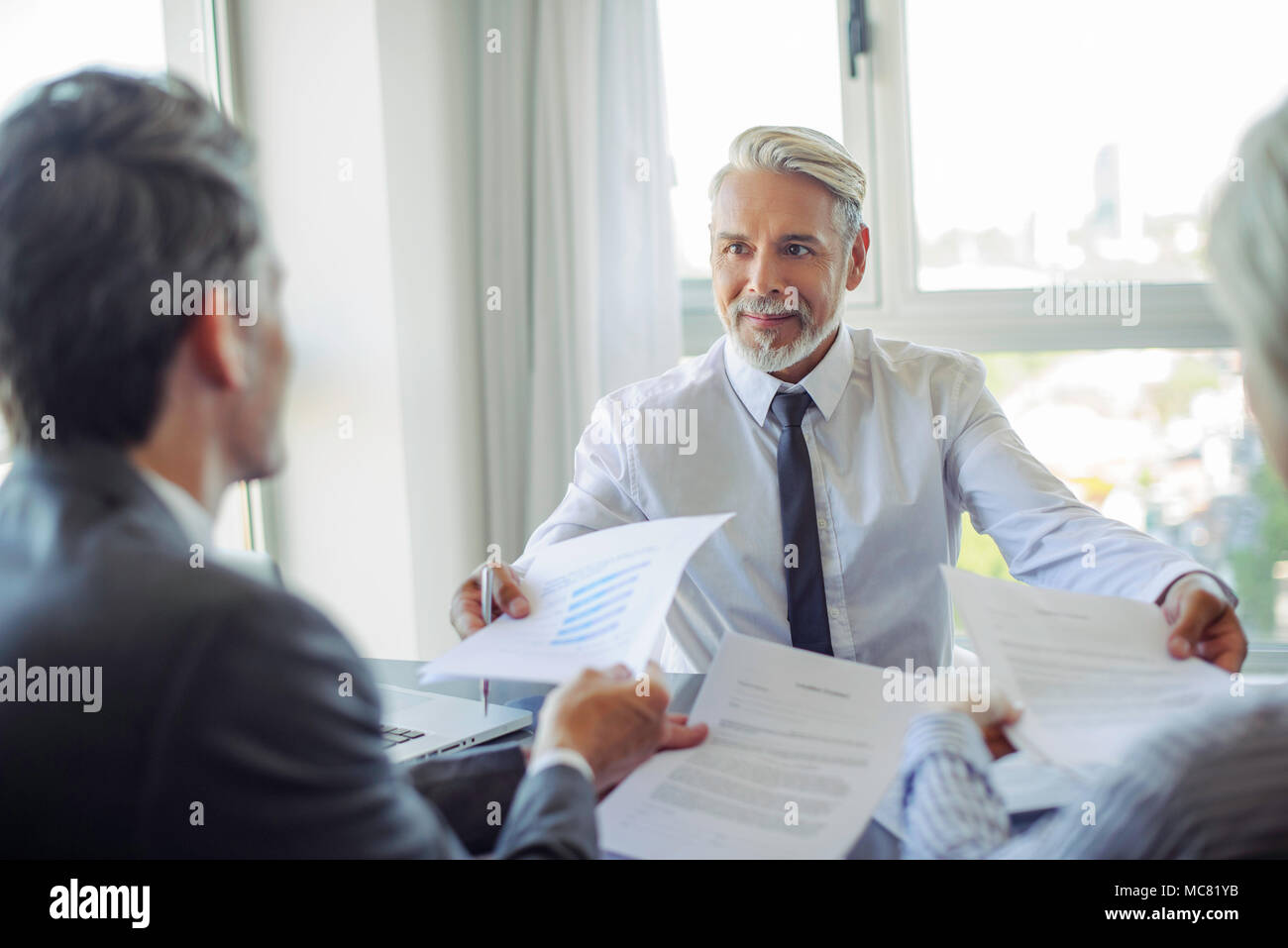 Businessman handing documents to clients Stock Photo - Alamy