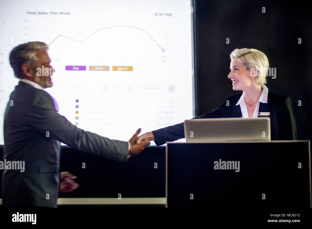 Man and woman shaking hands at podium Stock Photo - Alamy