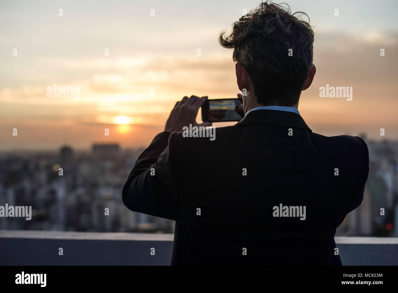 Man taking photograph of sunset Stock Photo - Alamy