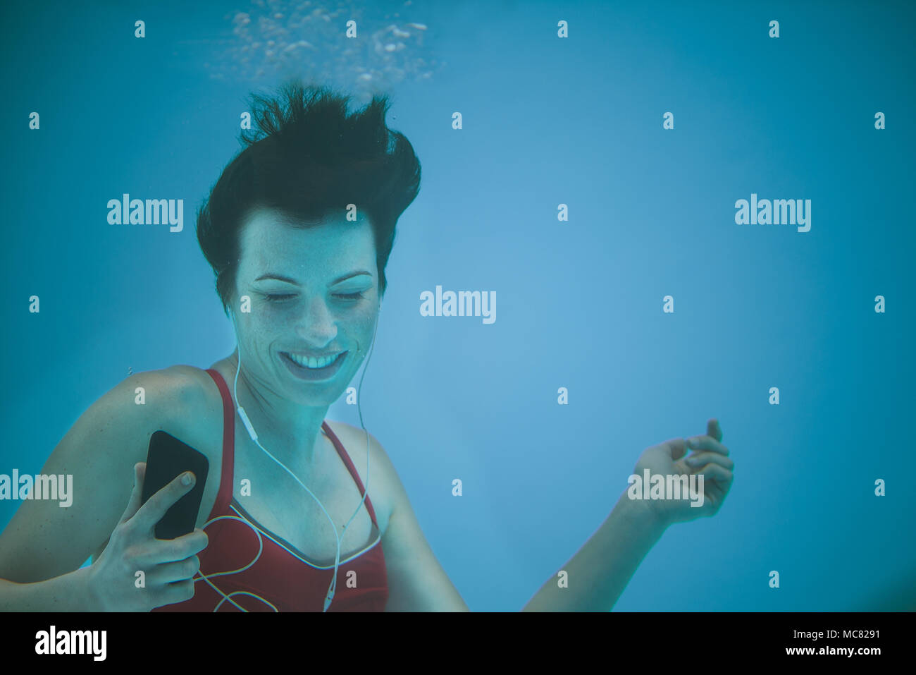 Woman listening to music with smartphone underwater Stock Photo - Alamy