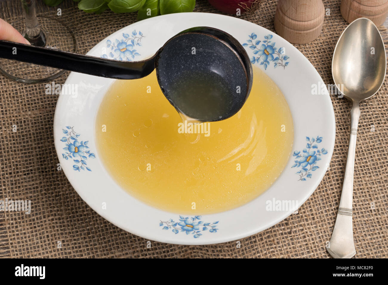 Pouring chicken bone broth into a soup plate with a ladle Stock Photo ...