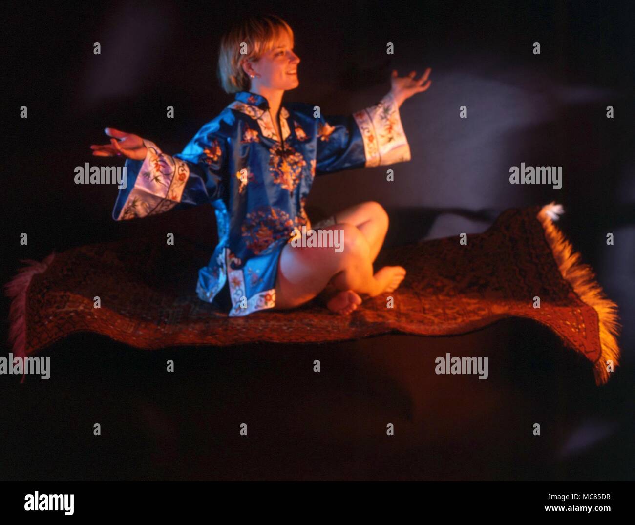 Levitation. Young girl flying, or levitating, on a magic carpet - a ...