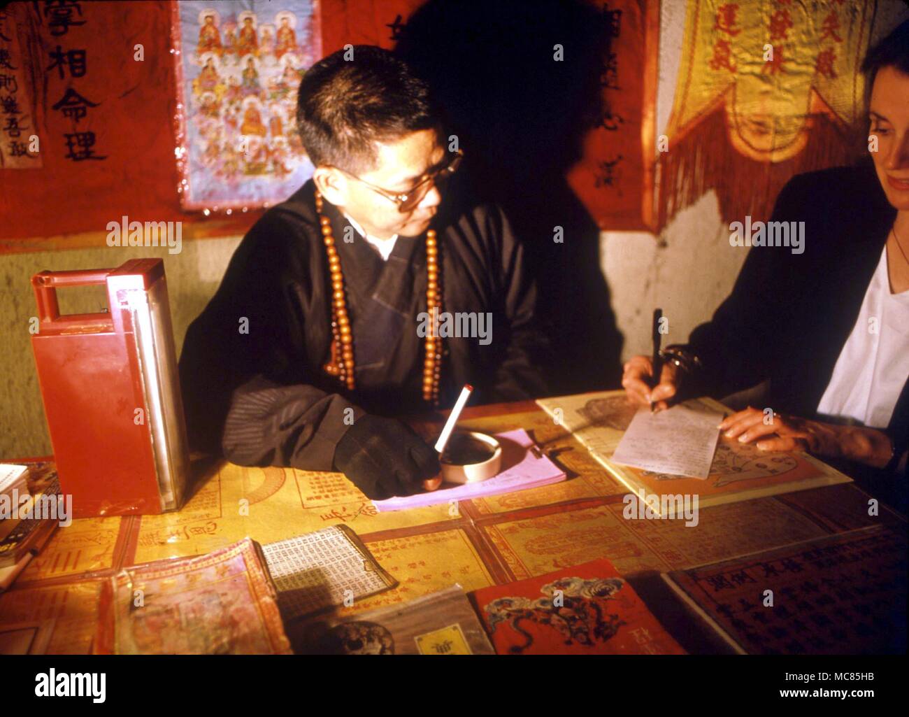 Chinese fortune teller and palmist, consulting with clients, in Temple ...