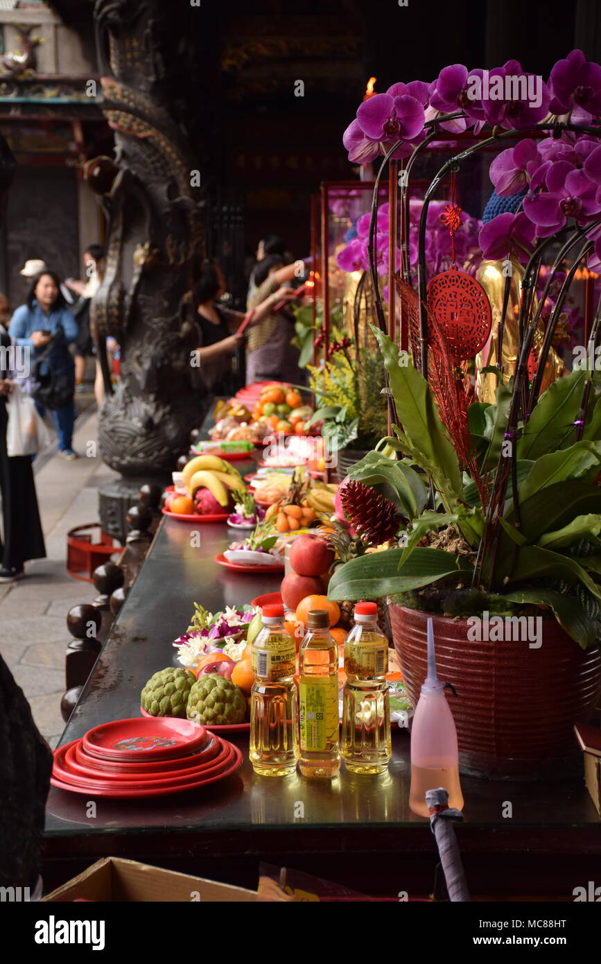 Food, fruits, flowers and other offerings on a table inside Longshan ...